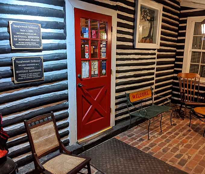 That red door and log cabin exterior: your first clue that something special awaits inside this historic spot.