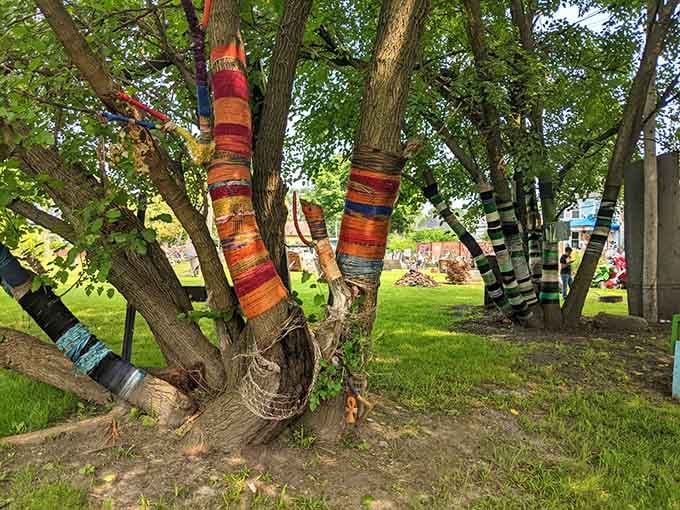 Trees wrapped in colorful fabric strips stand like nature's candy canes, blending organic growth with human creativity beautifully.