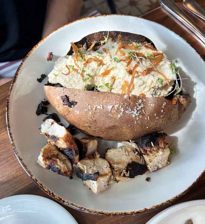 A loaded sweet potato so stuffed with goodness it could moonlight as a full meal and nobody would complain.