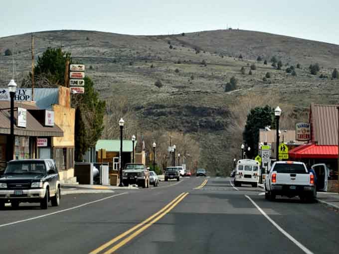 Hills rise behind main street like sleeping giants, their bare slopes a reminder of the rugged landscape surrounding town.