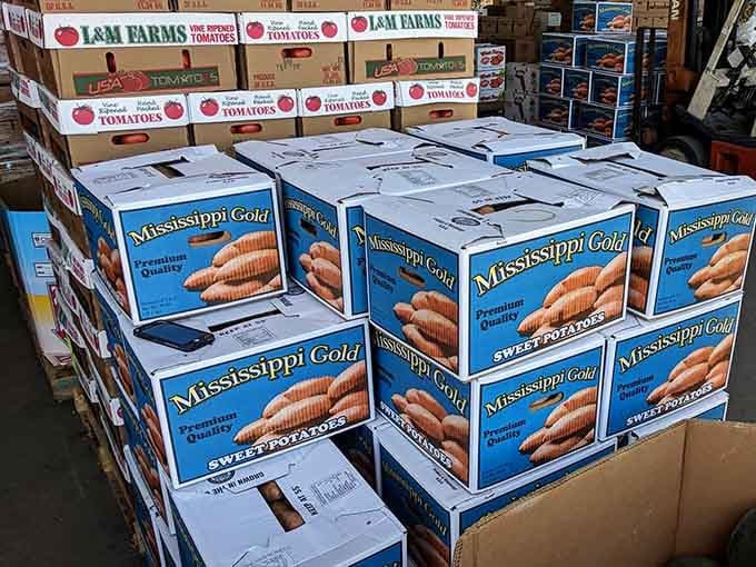 Boxes of sweet potatoes and tomatoes stacked high, ready for bulk buyers and serious home cooks alike.