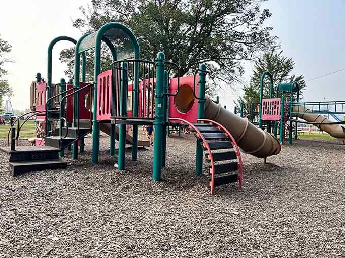 The playground's pink and teal equipment offers little ones their own adventures while parents catch their breath on nearby benches.