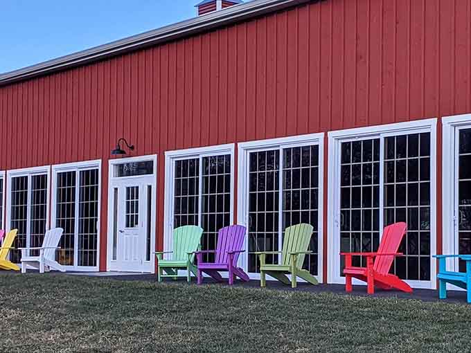 Rainbow seating outside a classic red barn suggests someone here understands that life's too short for boring furniture choices.