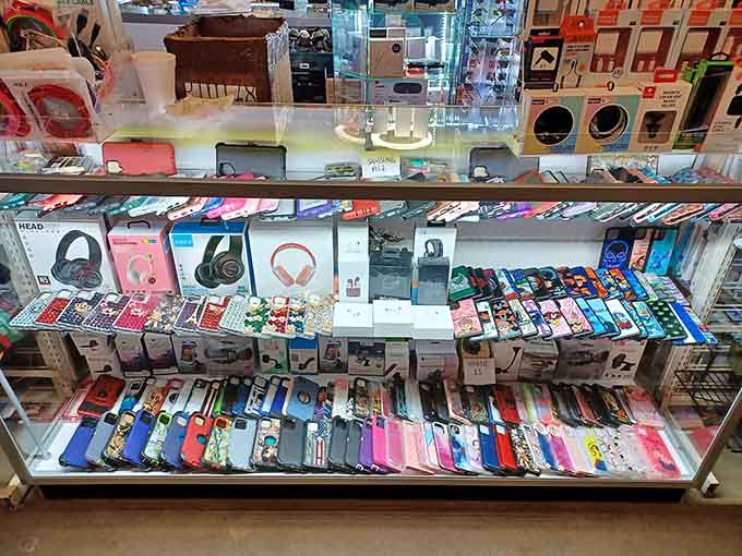 Phone accessories and headphones organized in a display case that sparkles like a jewelry store for gadgets.