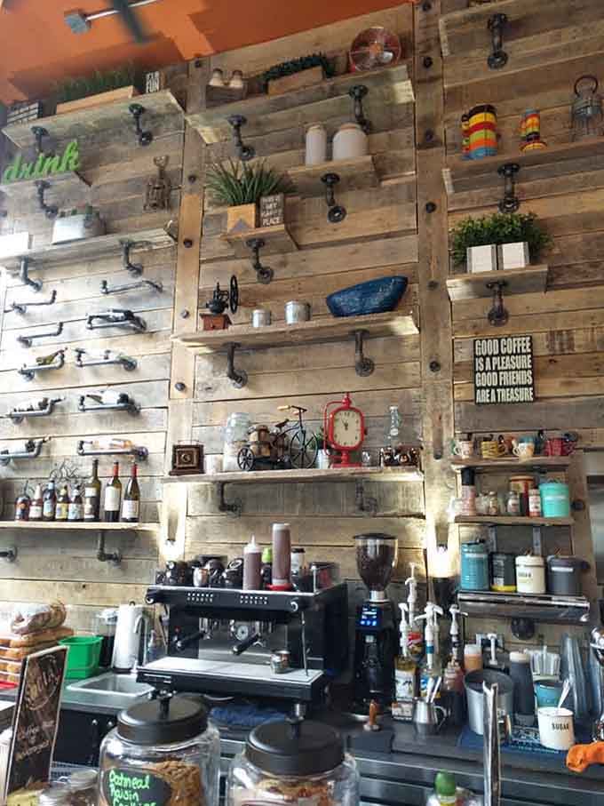 That wall of rustic shelving holds coffee equipment and quirky decor, turning caffeine preparation into an art installation worth admiring.