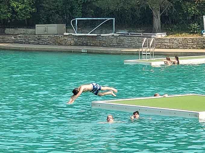Mid-dive suspension over impossibly clear quarry water captures that split-second of courage before gravity takes over and delivers pure summer joy.