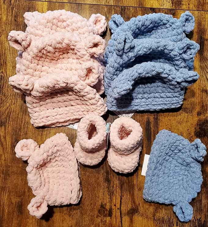 Soft knitted baby sets in pink and blue, handmade with the kind of care that makes store-bought items seem impersonal.