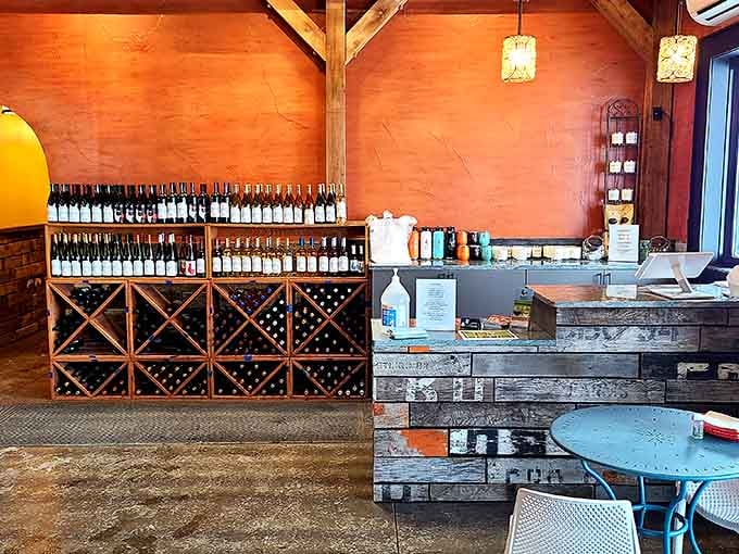 That warm orange wall behind the wine display creates an inviting glow that practically pulls you toward the tasting counter.
