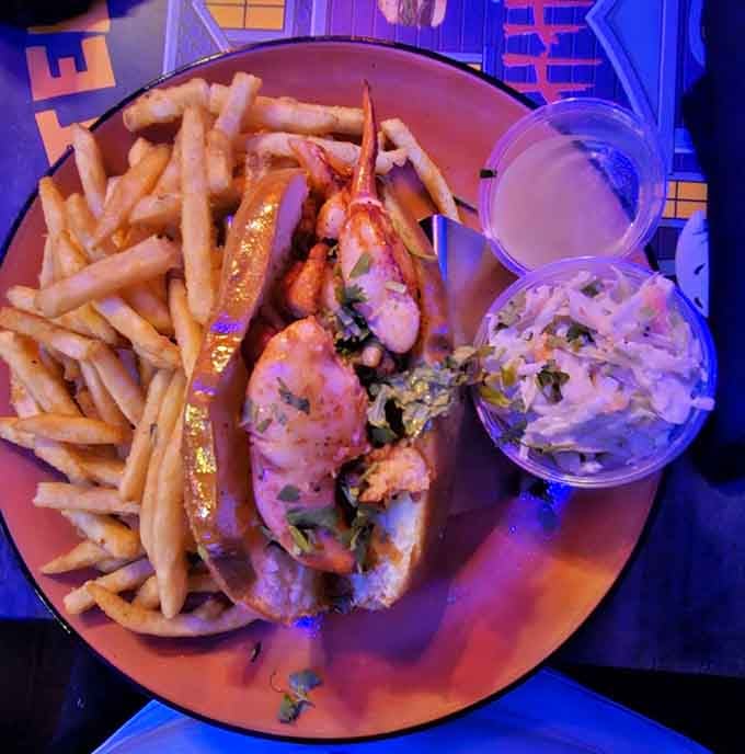 A lobster roll sits alongside fries and coleslaw, offering seafood lovers a delicious break from the burger-heavy menu options.