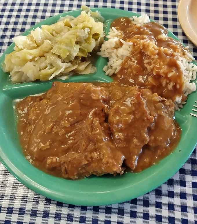 Country fried steak swimming in brown gravy with cabbage and rice. Comfort food at its finest.