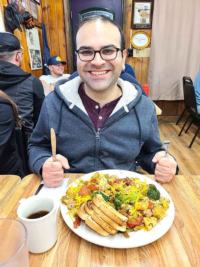 One happy customer with a loaded breakfast plate proves that sometimes the best meals require both hands and zero pretension.