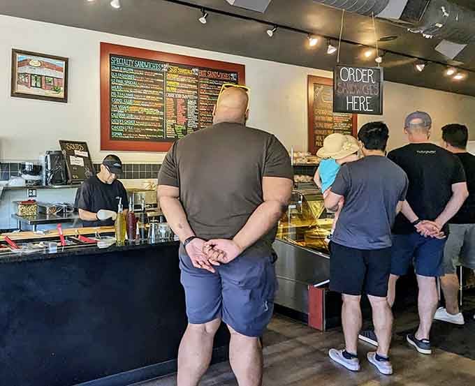 Customers waiting patiently, hands clasped, contemplating which sandwich will change their life today&mdash;it's a tough call.