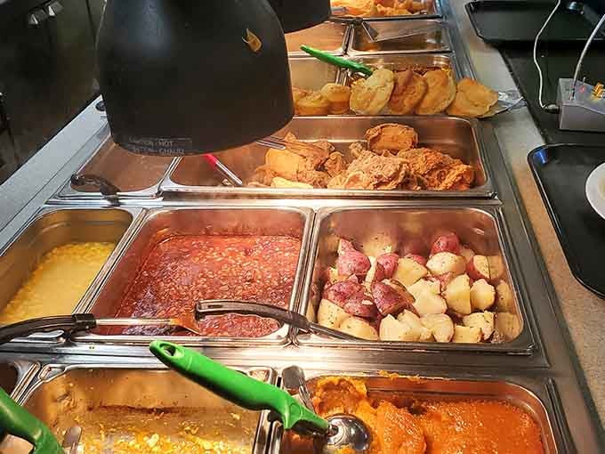 The steam table lineup showcasing fried chicken, sides, and biscuits is basically Southern comfort in buffet form.