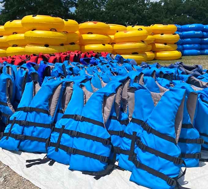 A sea of blue life jackets and yellow tubes standing ready, like a colorful army prepared for relaxation warfare.