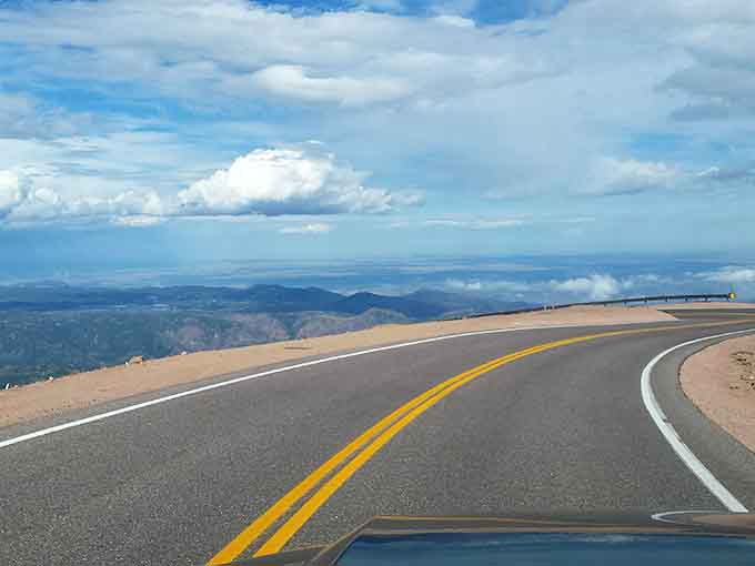 Blue skies and open road stretch toward distant horizons where earth finally surrenders to endless sky.