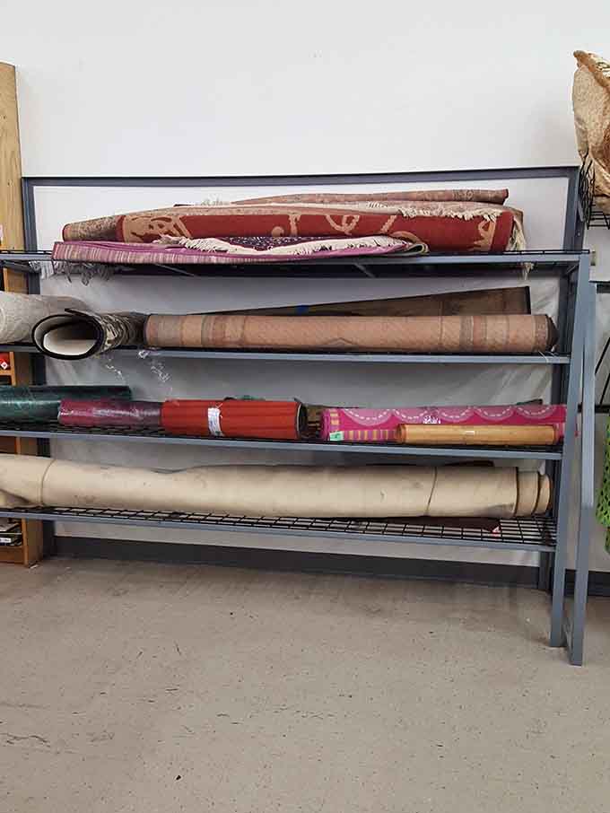 Rolled rugs rest like sleeping giants, each one hiding potential magic for your bare floors back home.