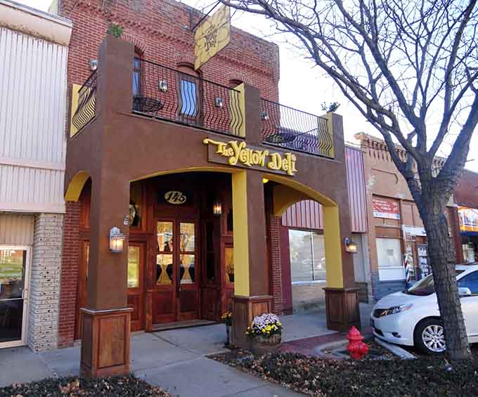 The Yellow Deli's distinctive facade with its arched entrance and warm lighting promises hearty sandwiches in a welcoming downtown setting.