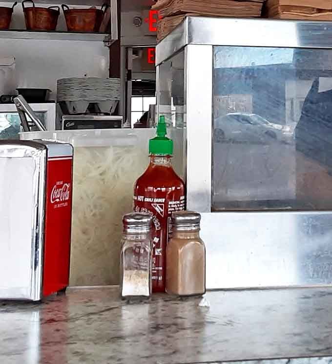 The holy trinity of condiments sits ready: ketchup, hot sauce, and the salt and pepper of destiny.