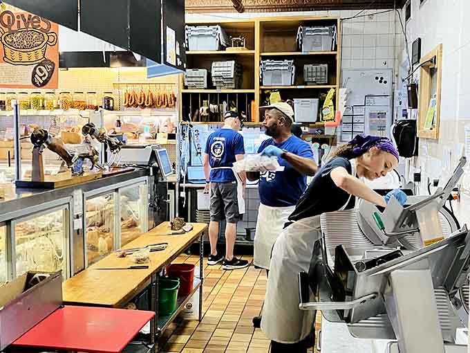 Behind the counter, skilled hands work the slicer, transforming quality ingredients into sandwich masterpieces with practiced precision.
