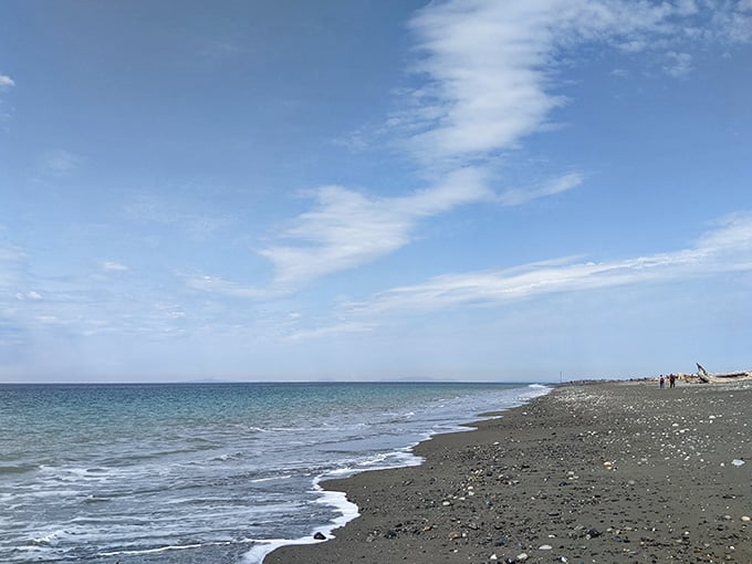 Gentle waves lap at the pebbly shore under wispy clouds, creating the kind of tranquil scene that lowers blood pressure instantly.