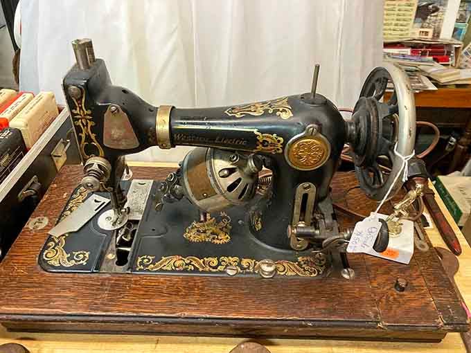 That ornate sewing machine with golden scrollwork once stitched wedding dresses and Sunday suits with precision modern machines can't match.