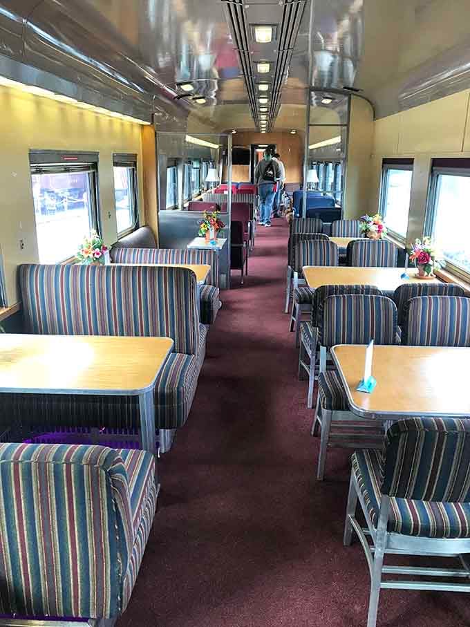 Interior seating features striped upholstery and tables, creating a dining car atmosphere that's both retro and comfortable.