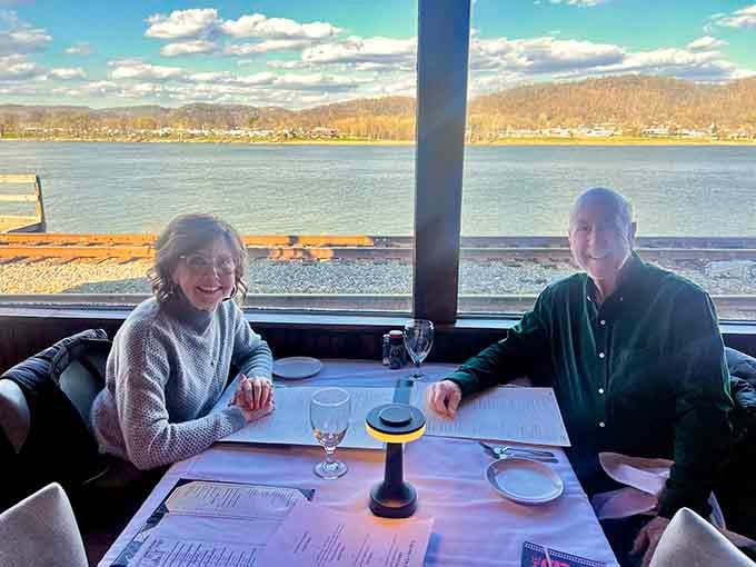 Two happy diners with the Ohio River sparkling behind them, capturing exactly why some restaurants become family traditions across generations.
