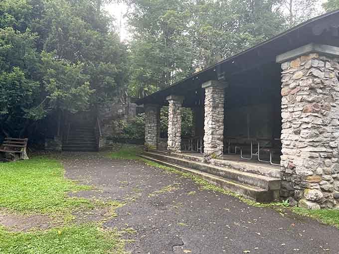 The stone pavilion provides shelter and gathering space, because even waterfall enthusiasts occasionally need shade and benches.