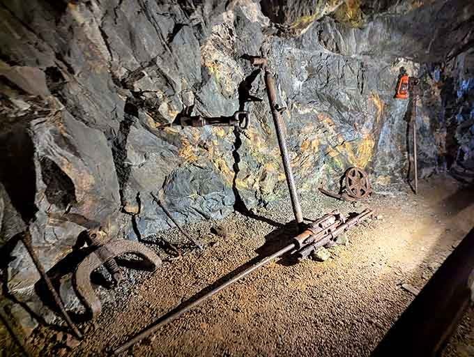 Vintage mining drills stand ready, reminding you that progress came one hole at a time down here.