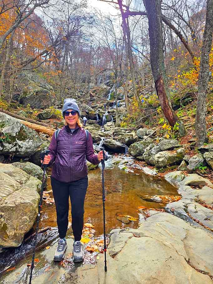 Standing victorious by the creek with hiking poles in hand, proof that the journey really is as rewarding as the destination