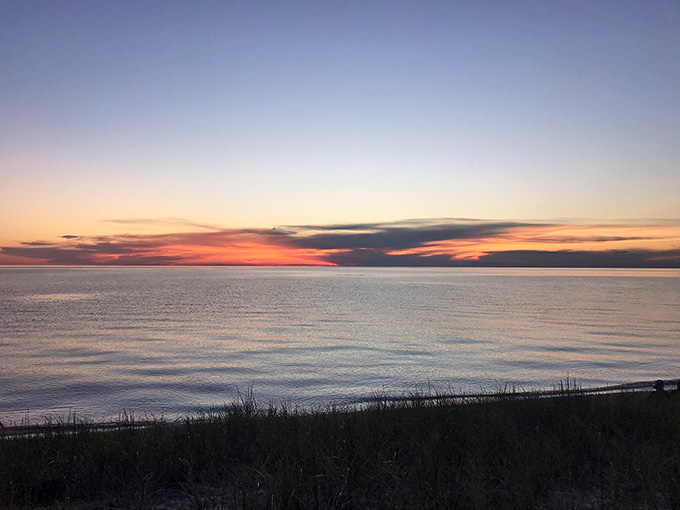 The sky blushing pink and orange over calm waters, nature's way of saying goodnight in the most spectacular fashion.