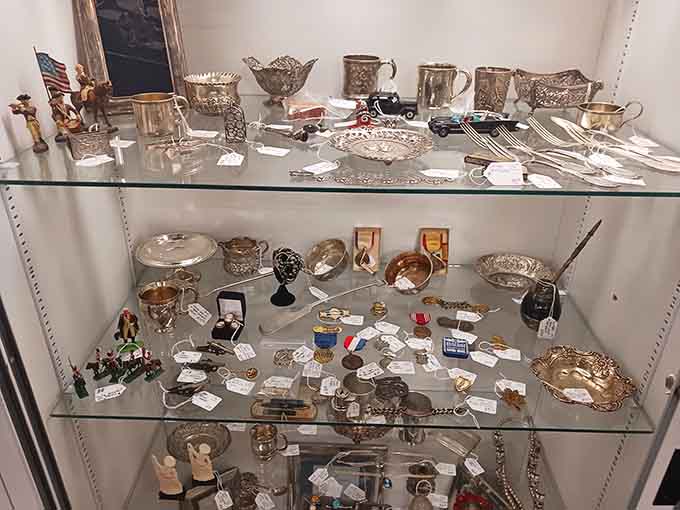 Vintage silverware and collectibles sparkling behind glass like tiny treasures in a very sophisticated pirate's chest.