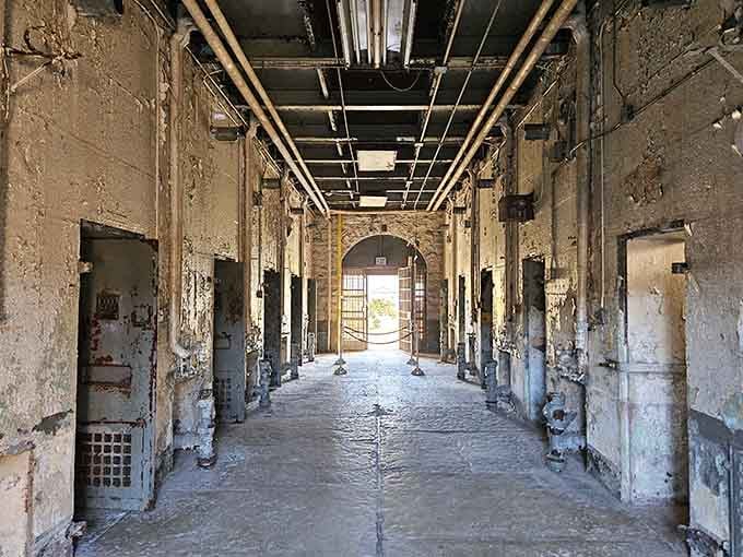 Open cell doors create haunting perspective down this corridor: freedom and confinement separated by just a few inches of steel.