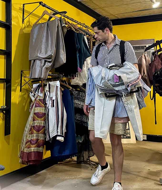 A shopper contemplates his finds, arms full of possibilities, living proof that thrift shopping is truly an art form.