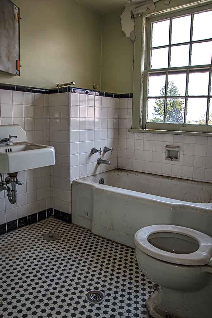 Classic black and white floor tiles meet vintage fixtures in a bathroom that time forgot but decay remembered.