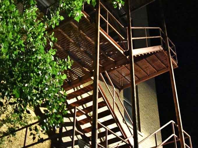 Rusted fire escape stairs cling to the building's exterior, offering an exit route for anyone with second thoughts mid-tour.