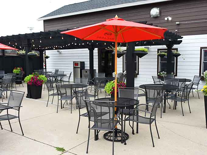 String lights, red umbrellas, and flower planters on a sunny patio. Summer dining doesn't get more inviting than this.