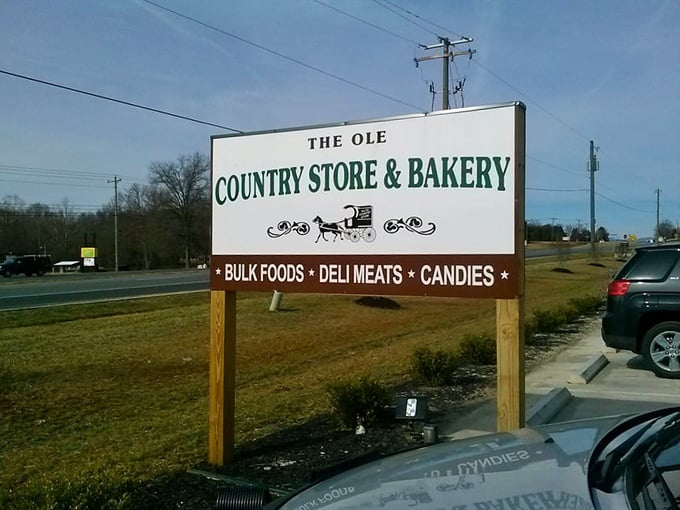 The roadside sign advertising bulk foods, deli meats, and candies, though honestly they're underselling the bakery situation inside.