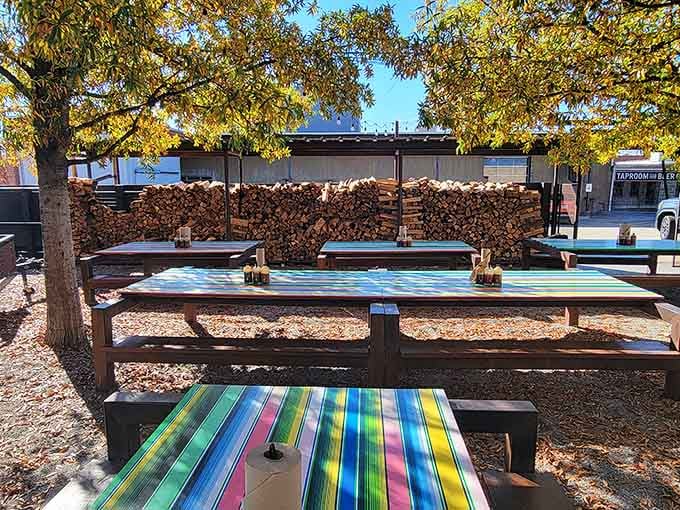 Colorful outdoor seating with stacked firewood in the background creates the perfect spot for enjoying barbecue alfresco.