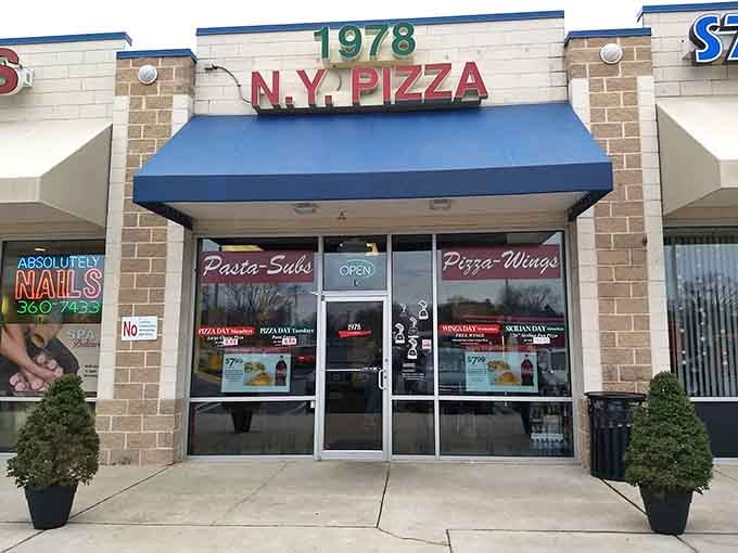 That blue awning and bold red lettering promise authentic New York-style pizza hiding in a Maryland strip mall.