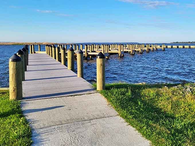 Wooden pier stretches endlessly into calm blue waters, inviting you to stroll toward solitude and serenity.