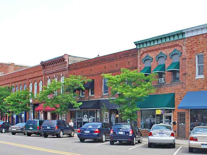 Classic brick storefronts line the street where green awnings shade windows full of treasures waiting to be discovered.