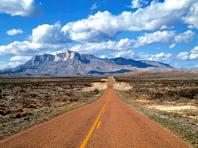 That red dirt road stretching toward those majestic mountains looks like a scene from every classic Western film.