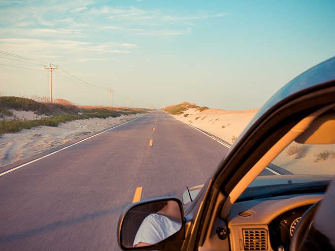 Golden hour on a coastal road where sand dunes meet endless pavement&mdash;this is freedom with a view.