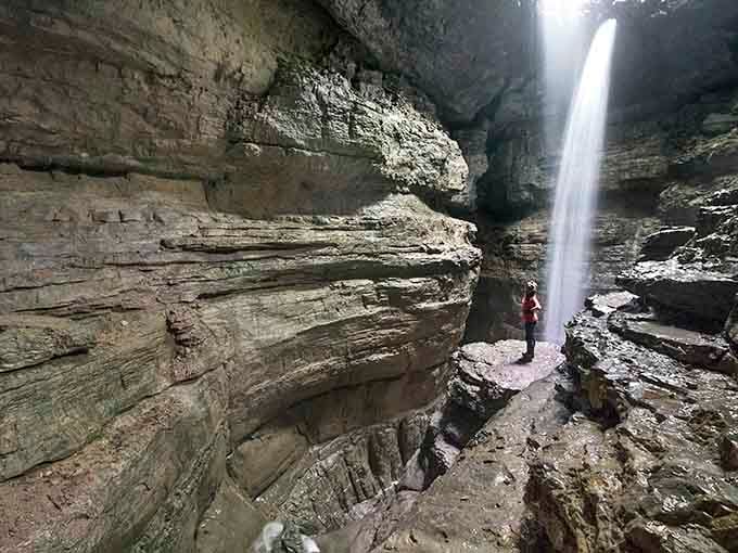 Mother Nature's spotlight shines through layered limestone walls, creating a waterfall stage that rivals any Broadway production.