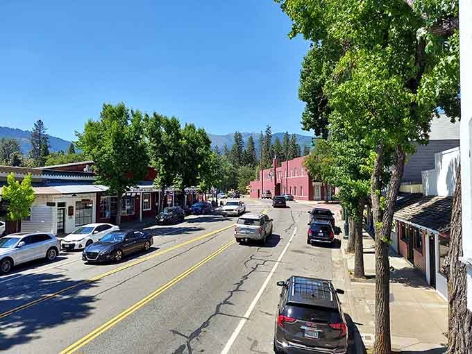 Main Street stretches out under blue skies, framed by towering trees and distant mountain peaks that whisper Gold Rush secrets.