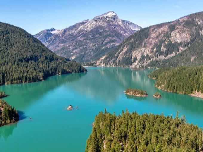 Snow-capped peaks frame this glacial masterpiece where tiny islands float like emeralds in liquid turquoise.