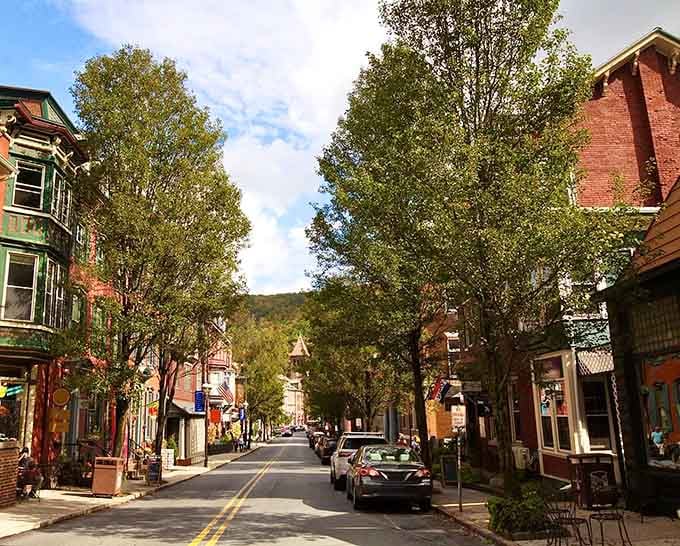 Tree-lined streets frame colorful storefronts perfectly, making every step feel like walking through a living postcard from another era.