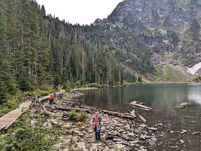 Hikers pause along the rocky shoreline where mountain reflections dance on Lake 22's impossibly blue surface.