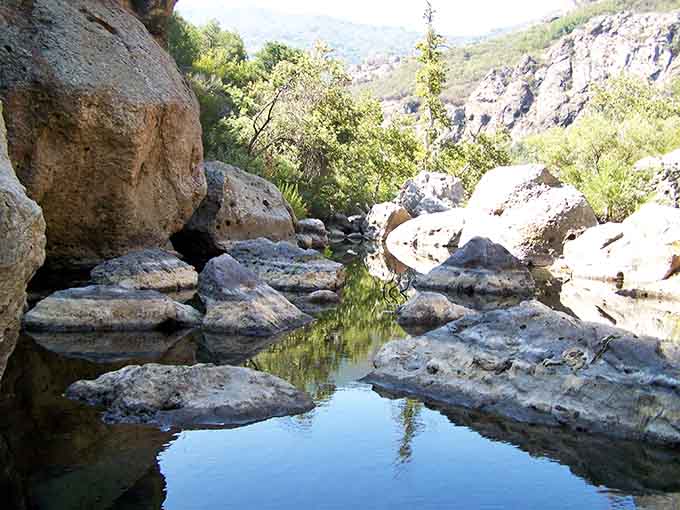 The canyon opens up to reveal still waters framed by weathered boulders, a peaceful hideaway worth the hike.